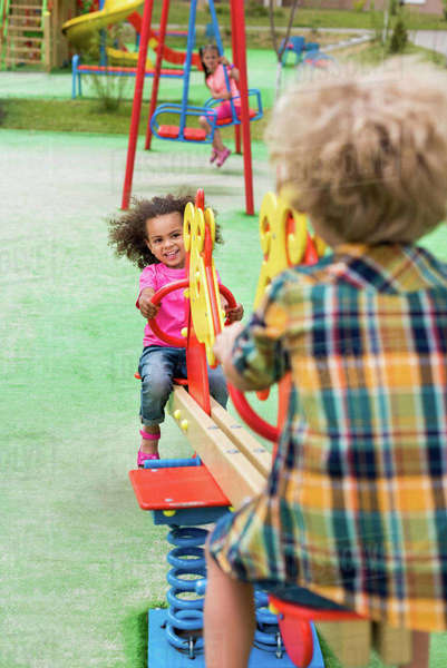 Rear view of boy riding on rocking horse with smiling african american ...