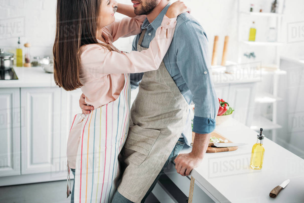 Couple cuddling and leaning on kitchen counter in kitchen - Royalty ...