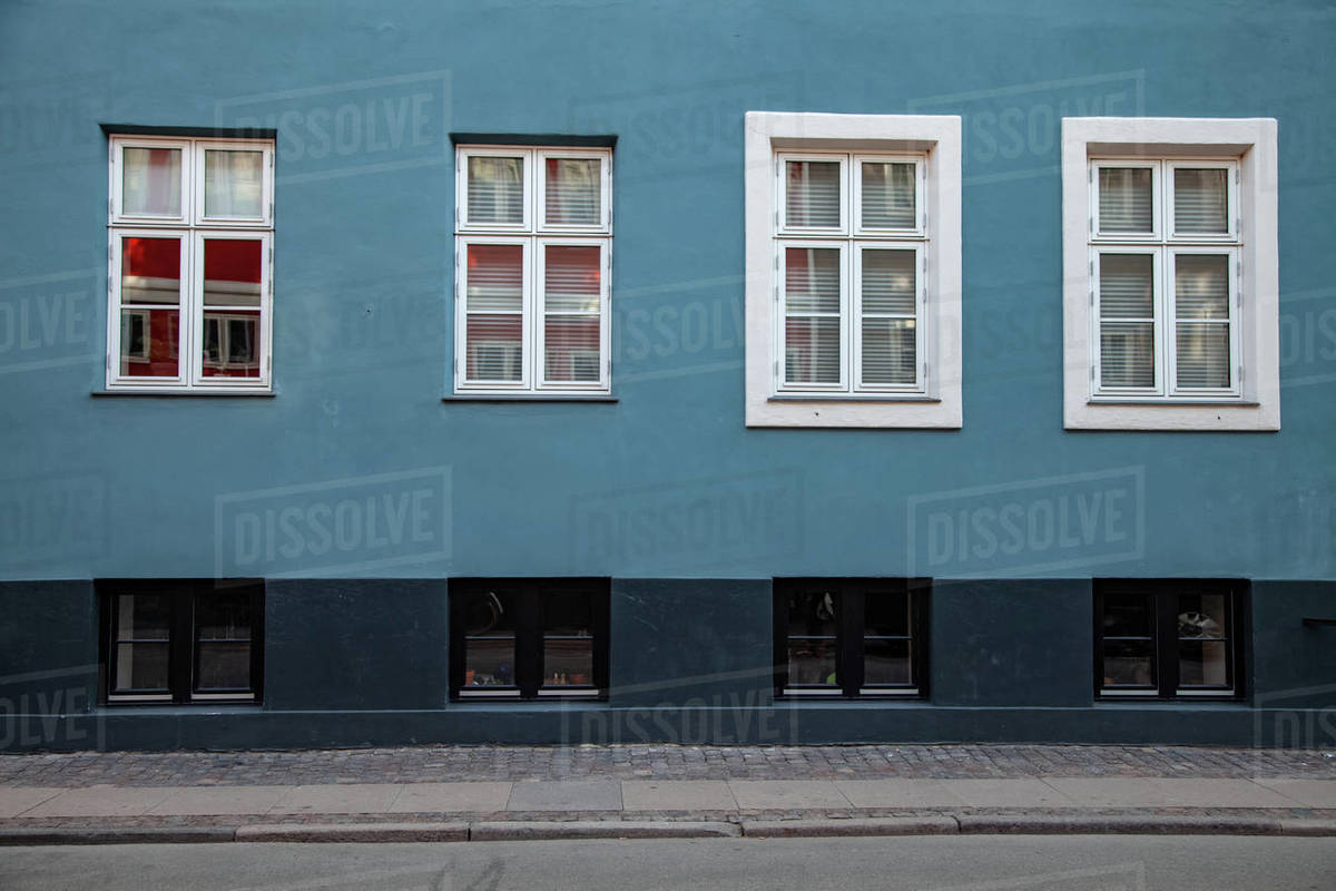 Detail of blue and grey building with white windows on street in ...