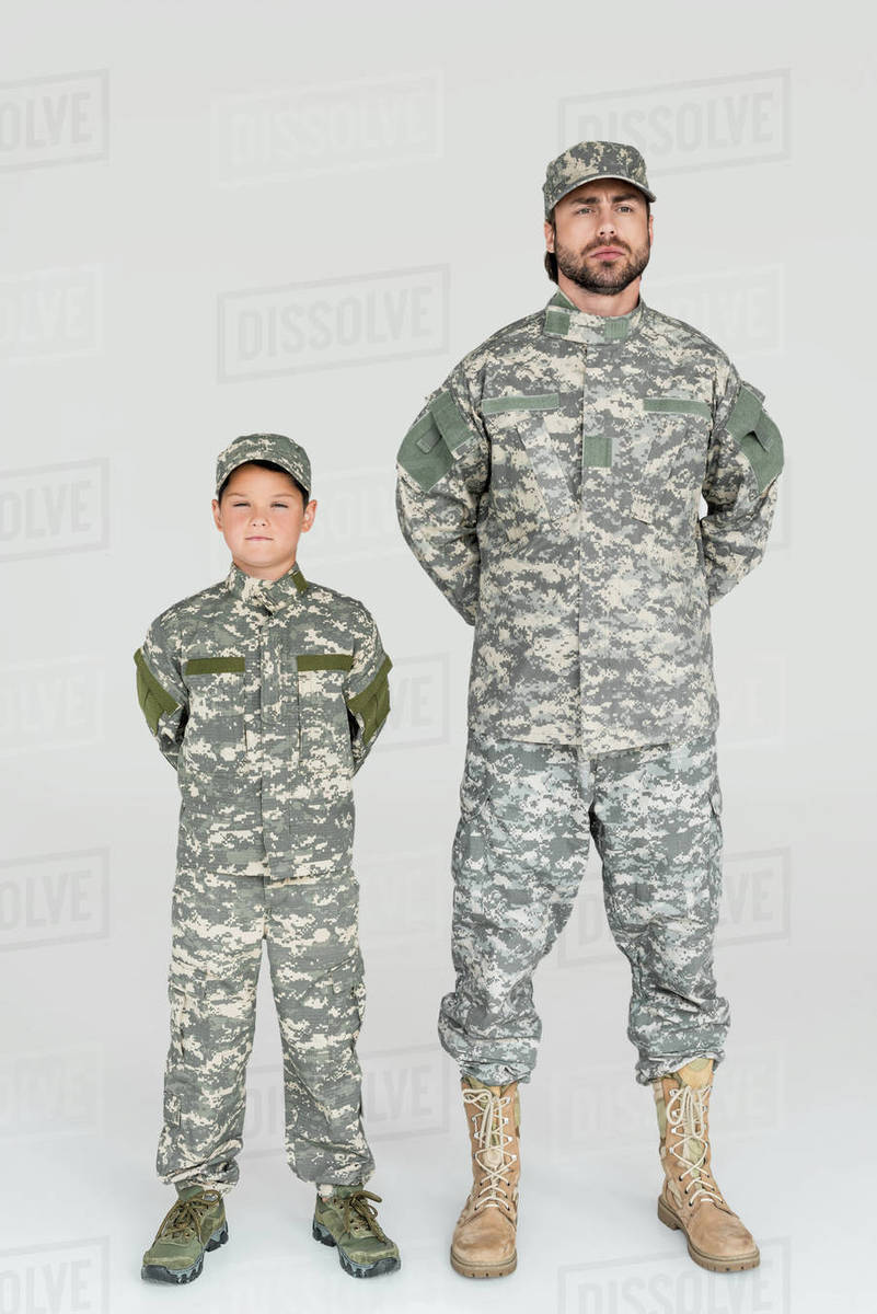 father and son in military uniforms looking at camera on grey ...