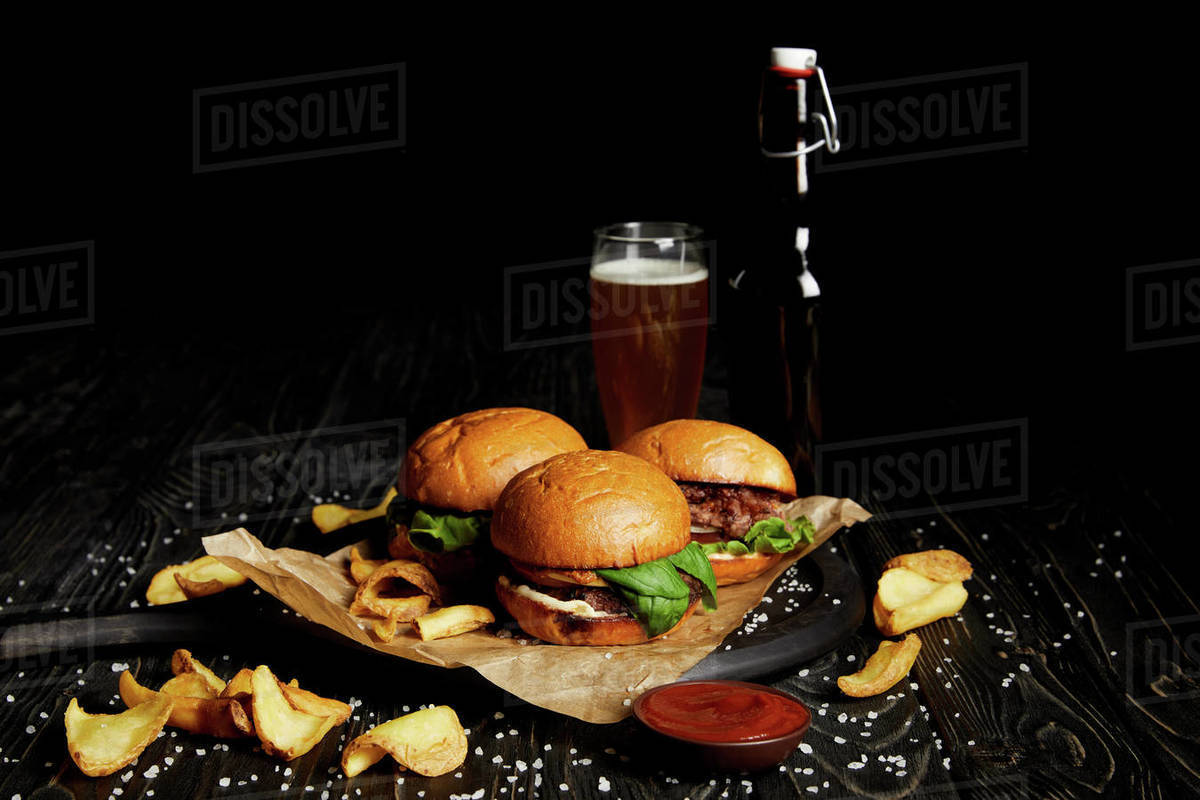 Set of junk food with burgers and french fries on table with beer in ...