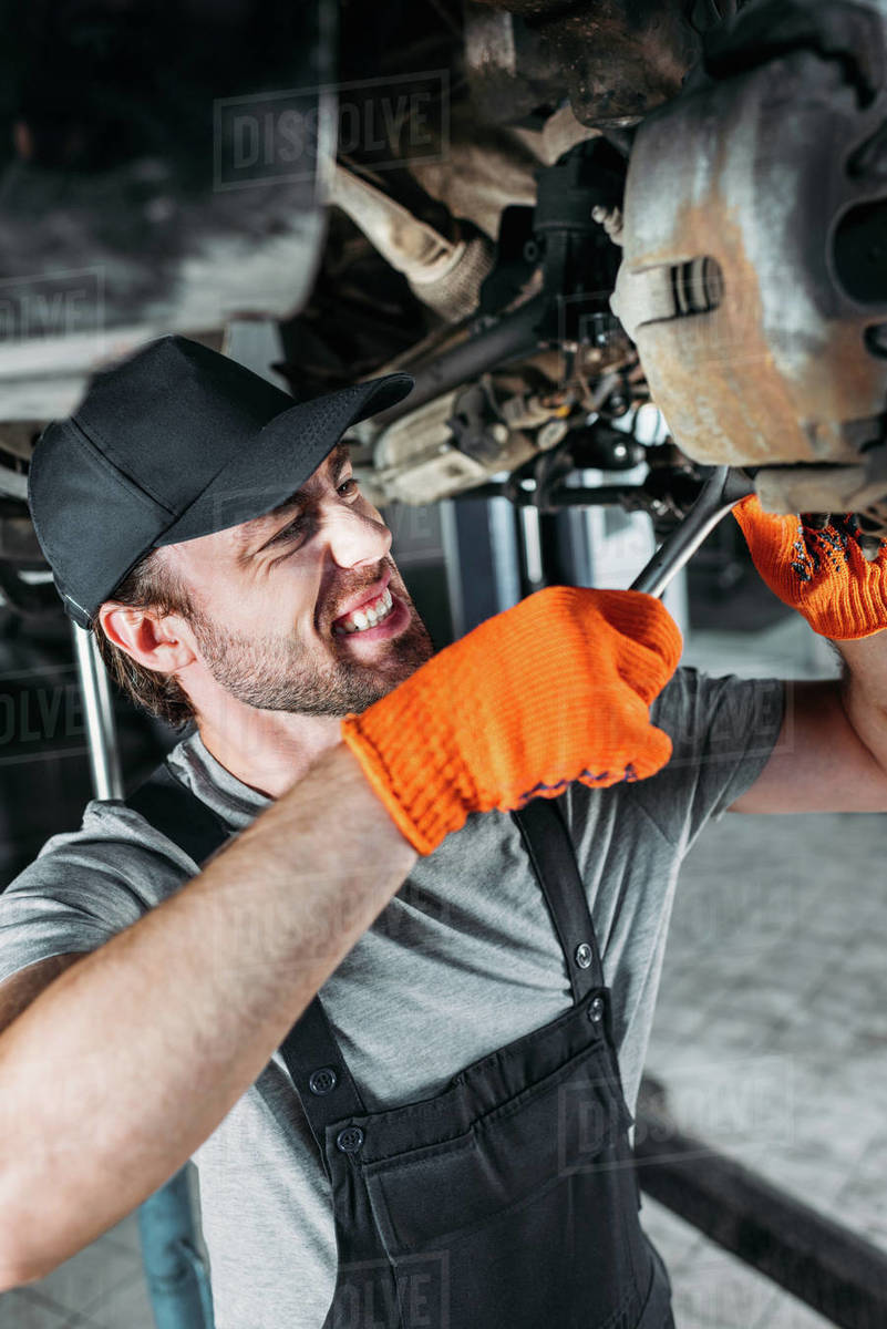 Professional mechanic repairing car without wheel in workshop - Royalty ...