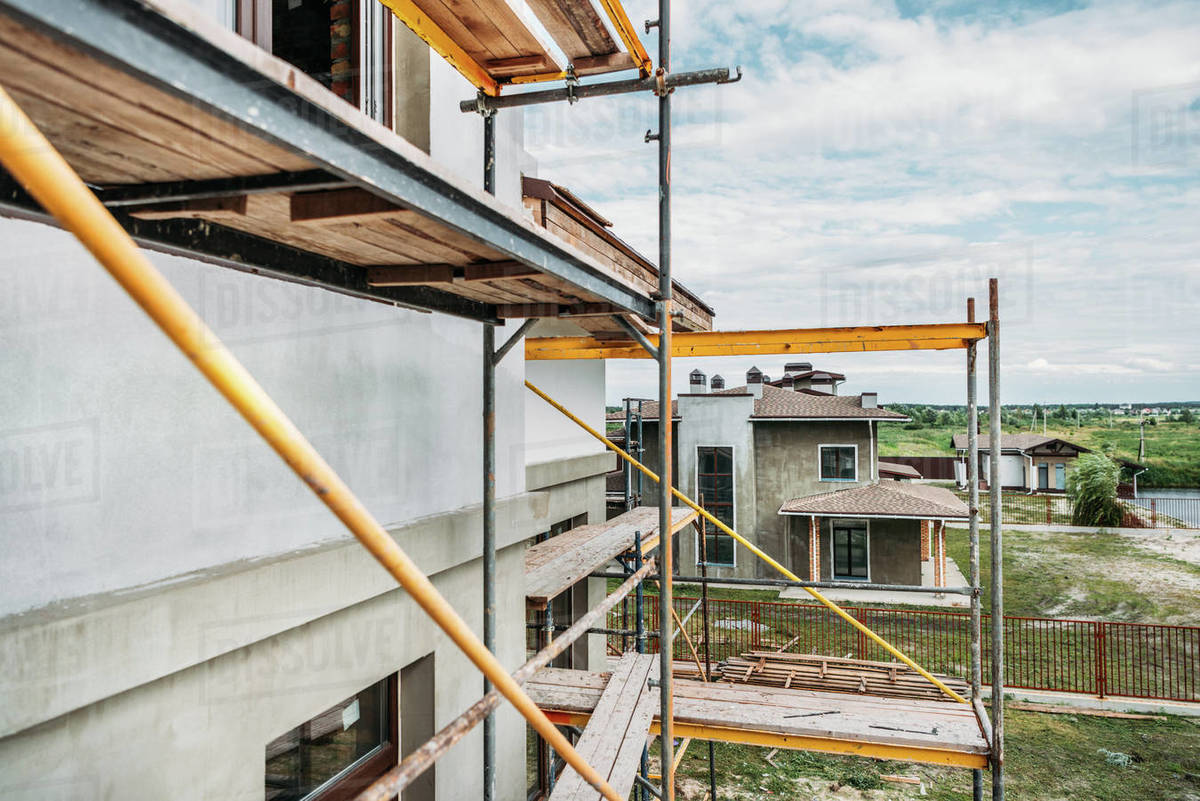 Scaffolding of construction site of modern building under cloudy sky ...