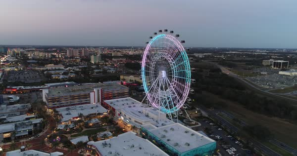Aerial circling the lit Orlando Eye with a view of downtown Orlando in ...