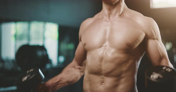 Muscular fitness man working out in the gym lifting dumbbells and ...