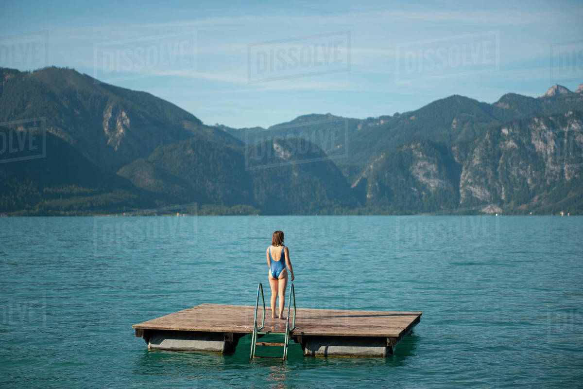 Woman in swimsuit standing on floating pier looking at water - Stock ...