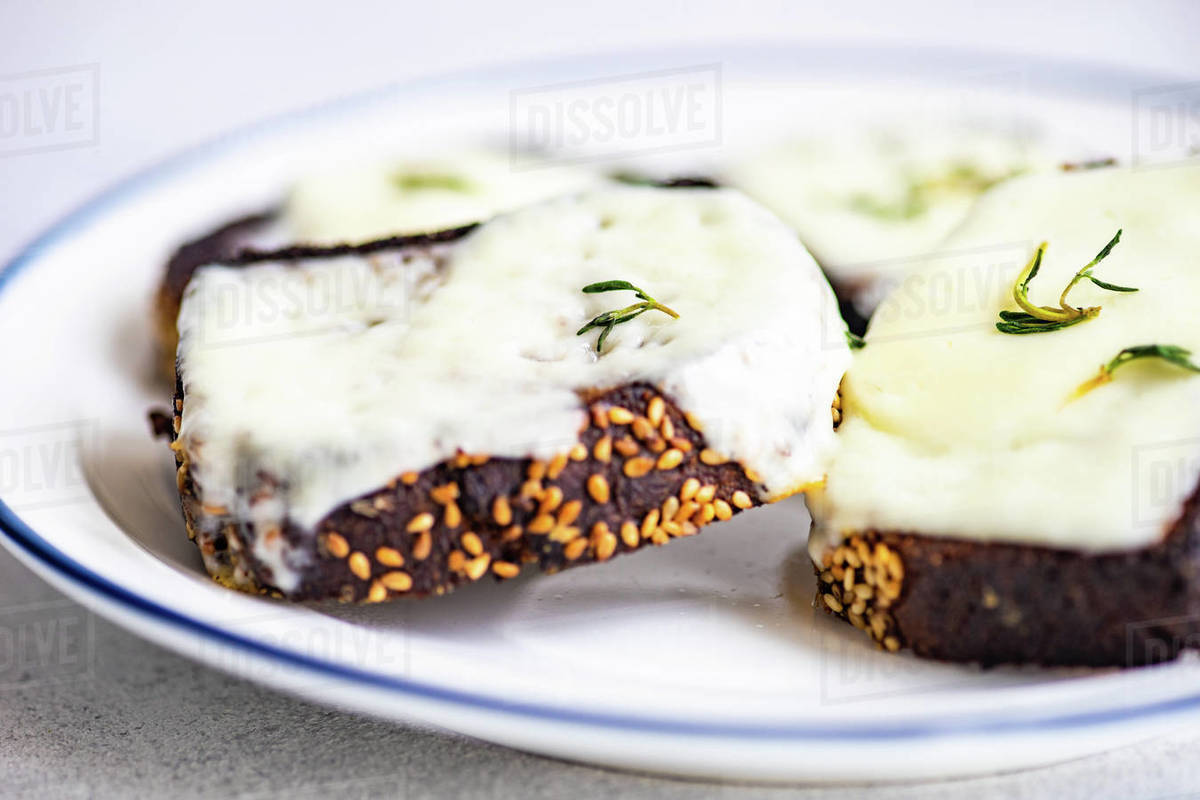 Close-up of a plate of rye bread toasts with melted cheese and fresh ...