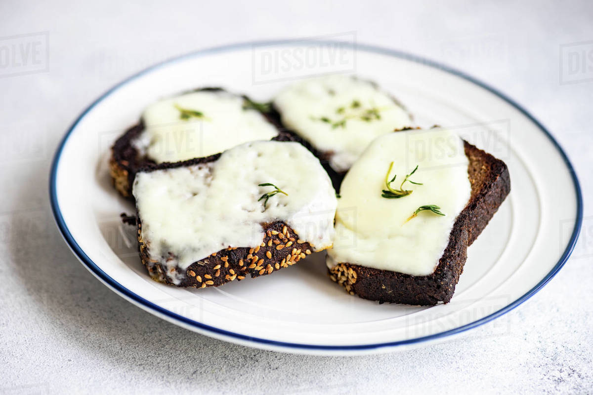 Close-up of a plate of rye bread toasts with melted cheese and fresh ...