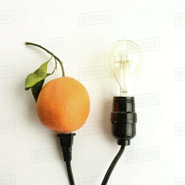 Light bulb plugged into an orange to illustrate Food generating clean ...