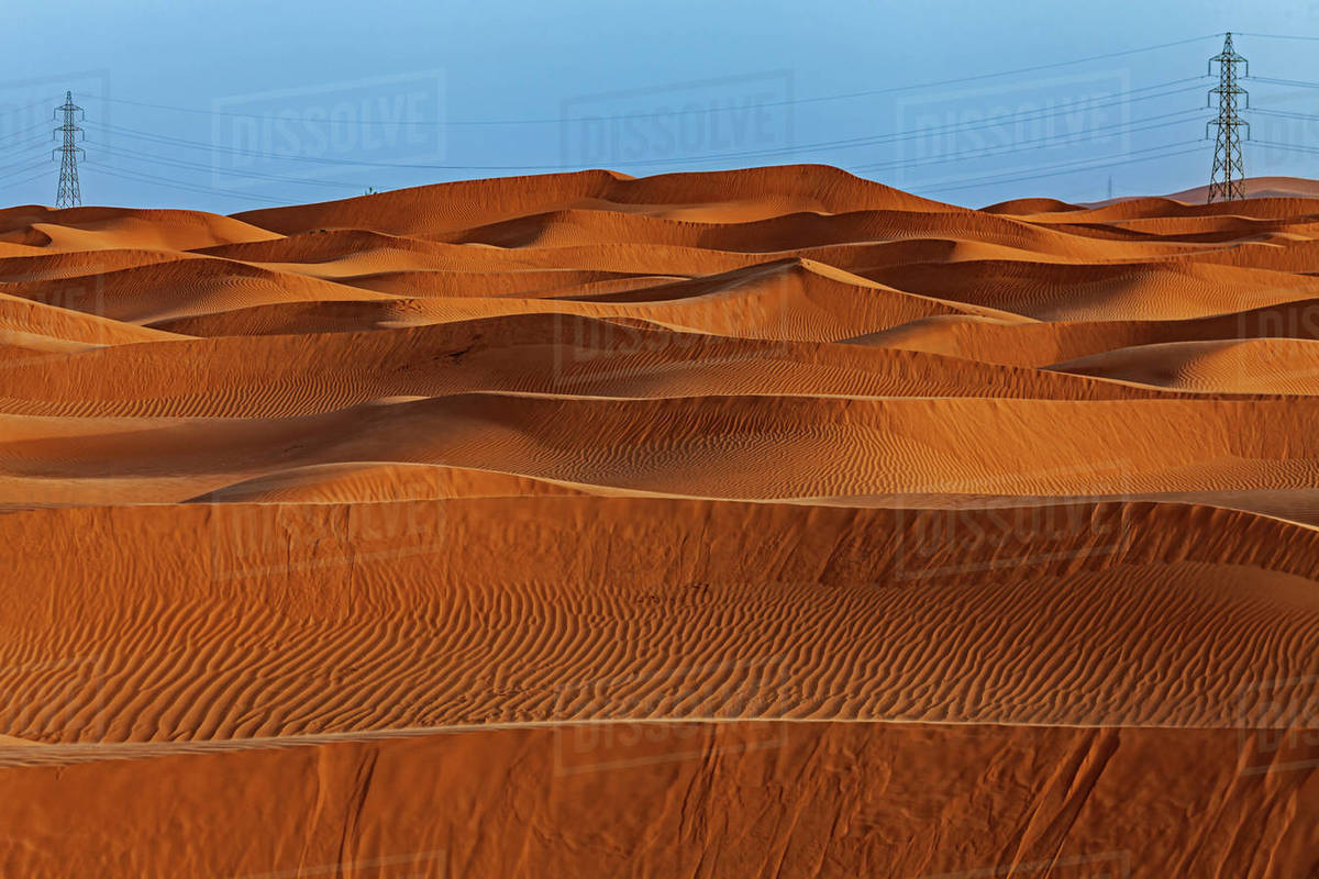 Electricity pylons amongst orange sand Dunes in desert, Saudi Arabia ...