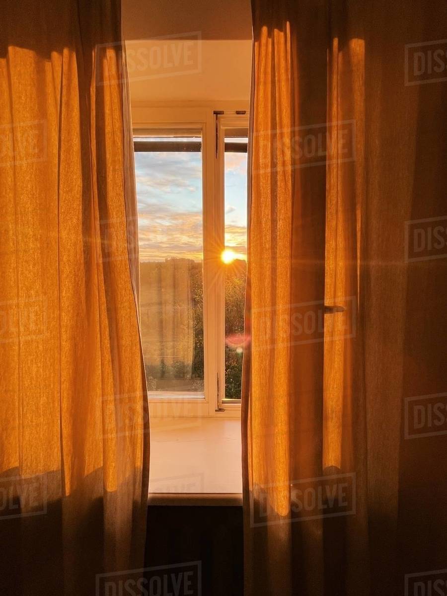 Sunrise through a window with half opened curtains - Stock Photo - Dissolve