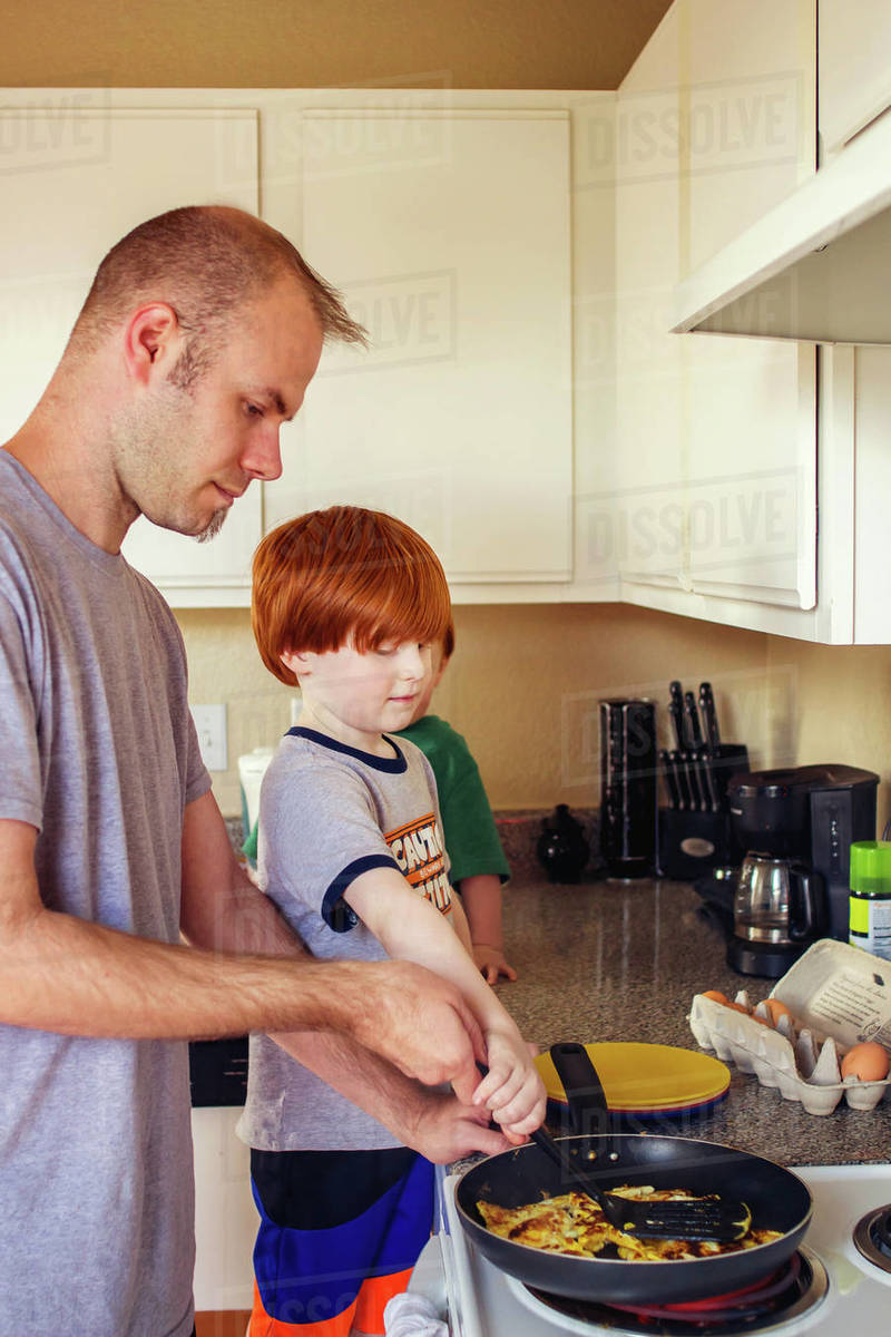 Two boys helping their father make eggs for breakfast - Royalty-free ...