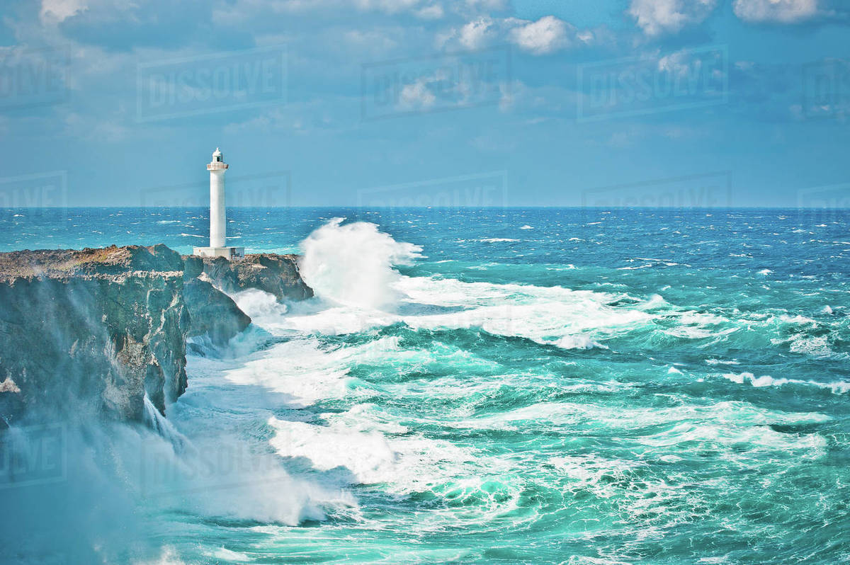 Waves crashing on rocks by a lighthouse in the wake of a typhoon ...