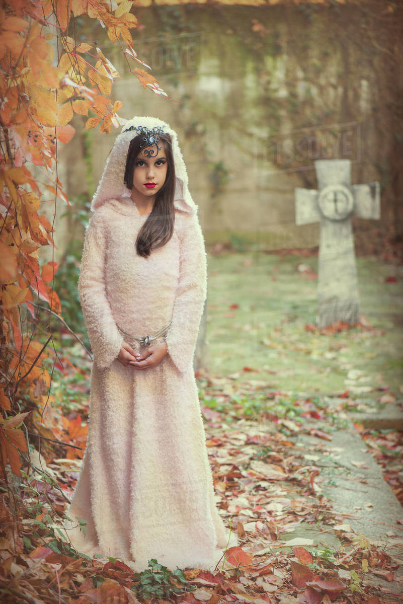 Portrait of a girl in halloween costume standing in a cemetery ...