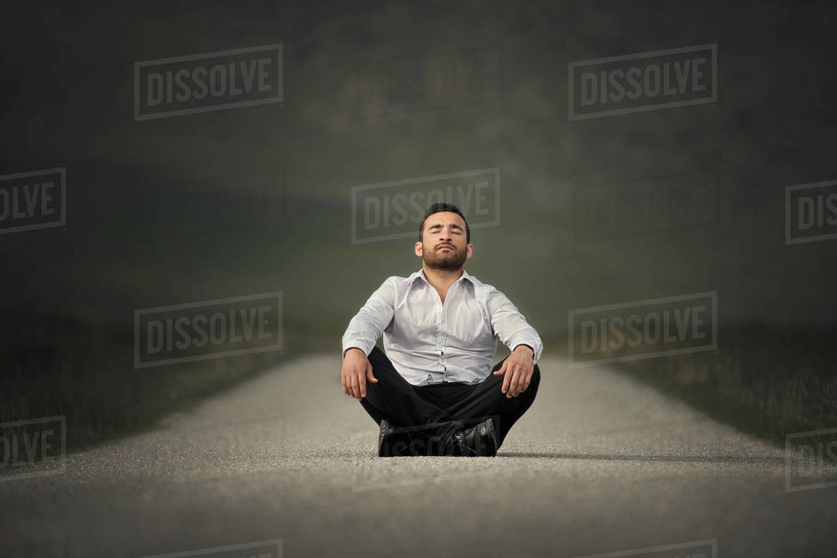 Portrait of a man sitting in the middle of a path meditating, Ireland ...