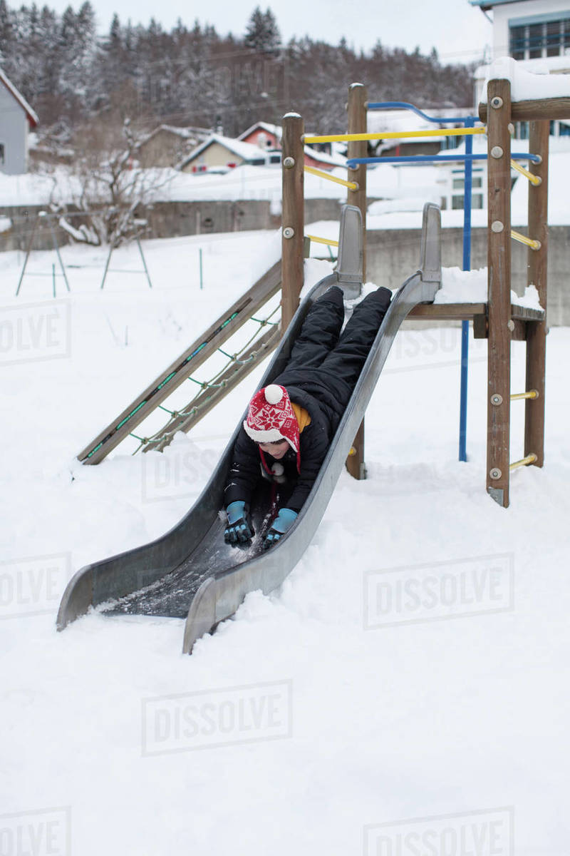 Boy sliding down a slide on his front - Royalty-free Stock Photo | Dissolve
