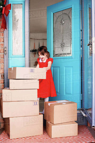 Girl standing by front door with delivery of boxes - Stock Photo - Dissolve