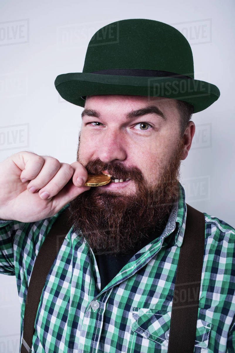 Portrait of a man biting a gold coin - Stock Photo - Dissolve