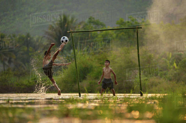 Two boys playing football in a waterlogged field, Thailand - Royalty ...