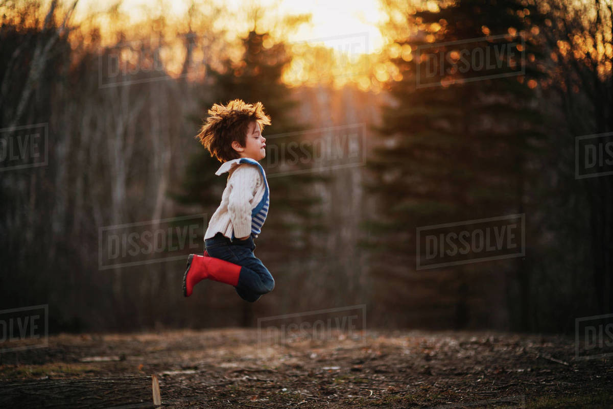 Boy jumping off a log in the forest - Royalty-free Stock Photo | Dissolve