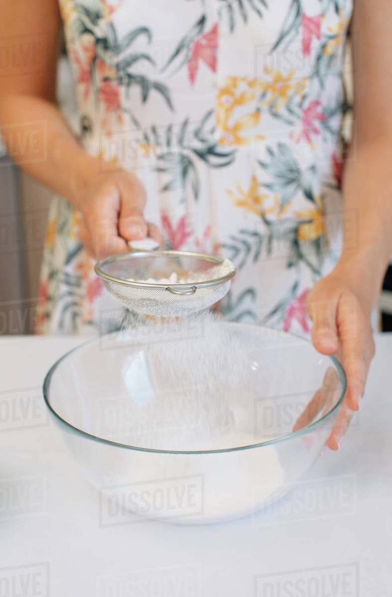 Woman standing in kitchen sifting flour into a bowl - Stock Photo ...