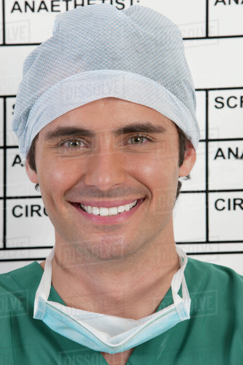Portrait of smiling surgeon in front of schedule board in hospital ...