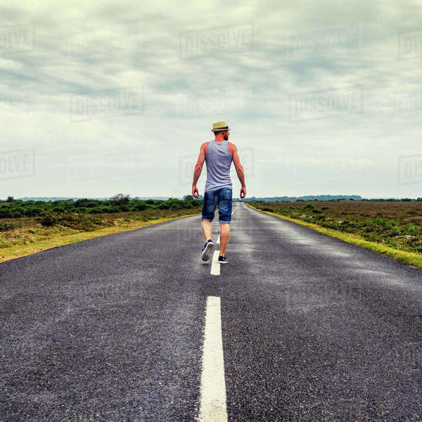 Man walking down the long road - Stock Photo - Dissolve