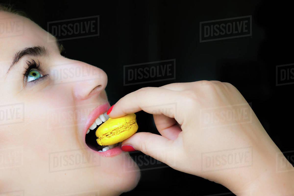 Woman eating macaroon - Royalty-free Stock Photo | Dissolve