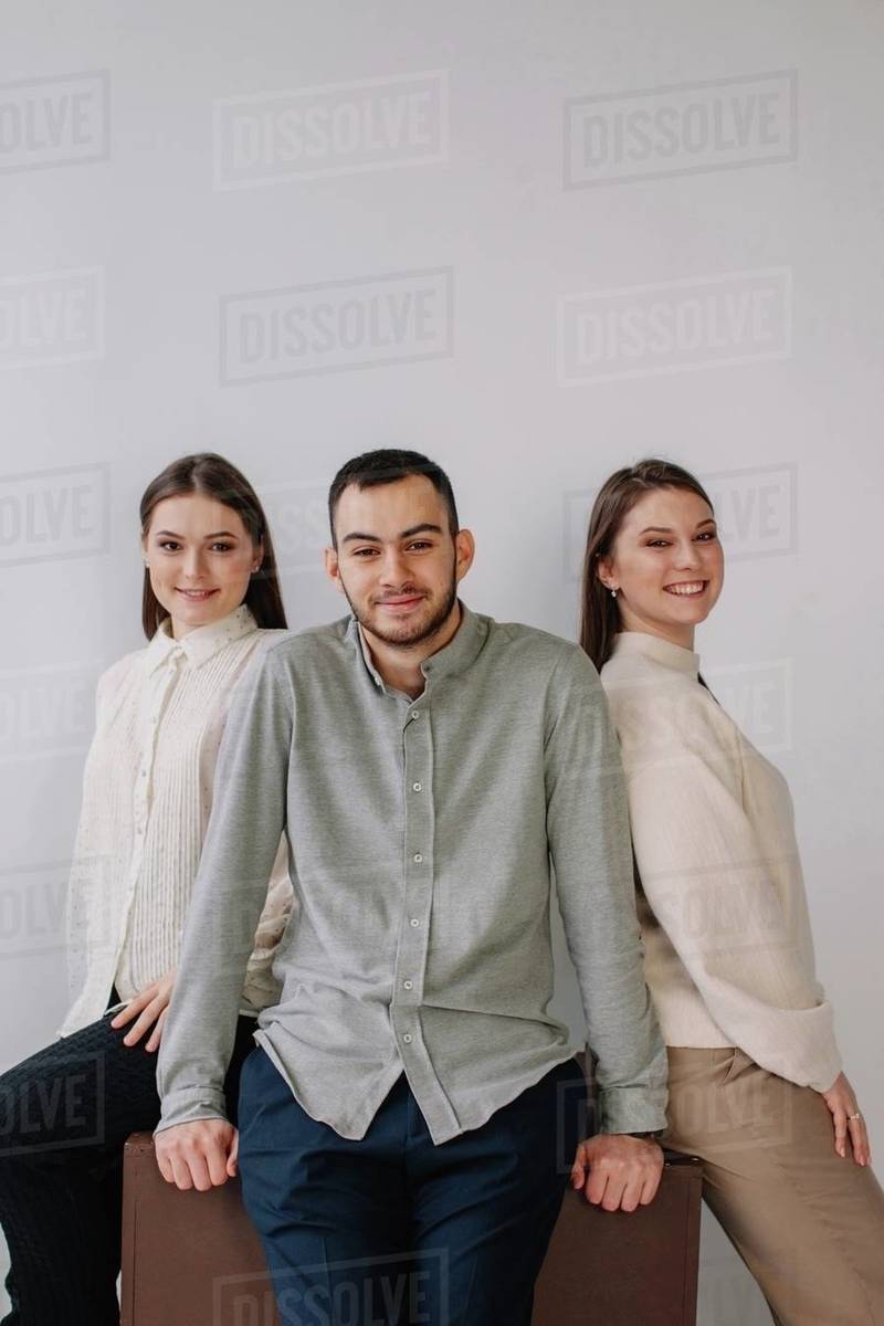 Portrait of three people sitting on the edge of a table - Royalty-free ...