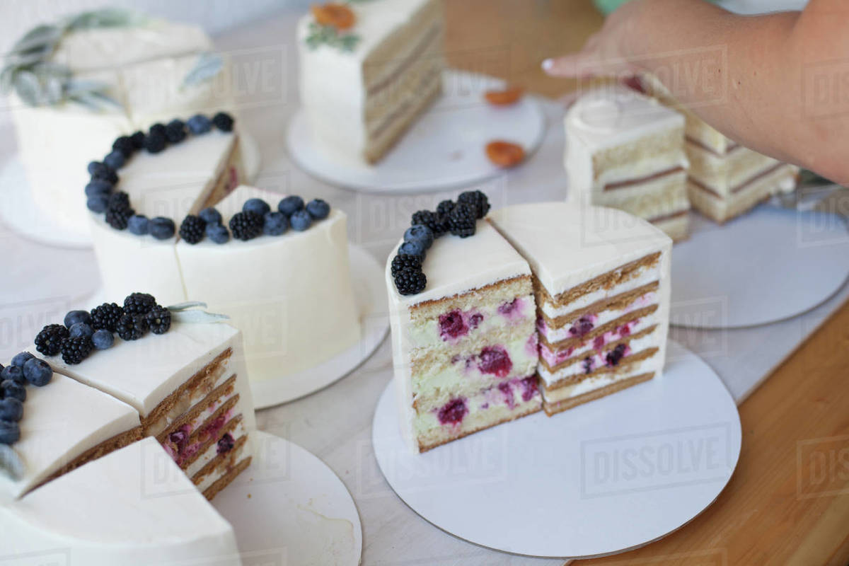 Woman's hand reaching for a slice of cake - Stock Photo - Dissolve