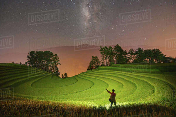 Man standing in terraced rice fields at night below milky way, Mu Cang ...