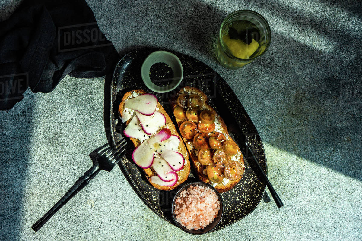 Overhead view of two wholegrain toasts with cheese, tomato, radish ...