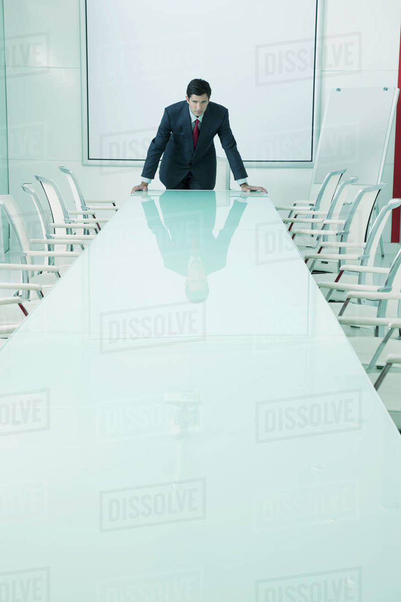 Businessman standing at the head of conference table in office - Stock ...