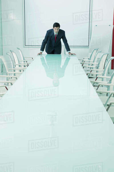 Businessman standing at the head of conference table in office ...