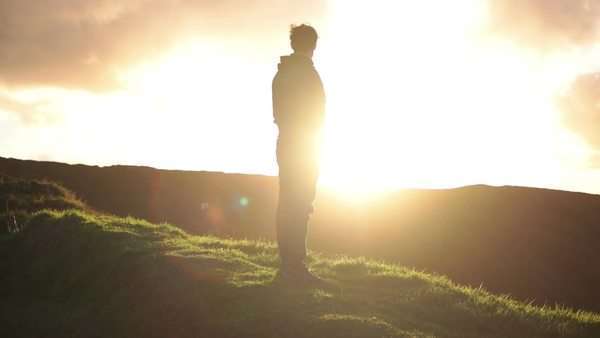 Man staring into the sunset, while seagulls flying in the background ...