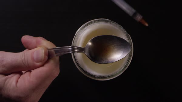 Top down view of brown heroin drugs getting cooked over a candle with a ...