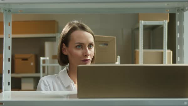 Woman employee of warehouse putting parcels on shelf, counting delivery ...