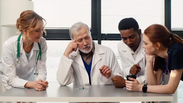 Medical team of multiethnic professional doctors looking at syringe ...