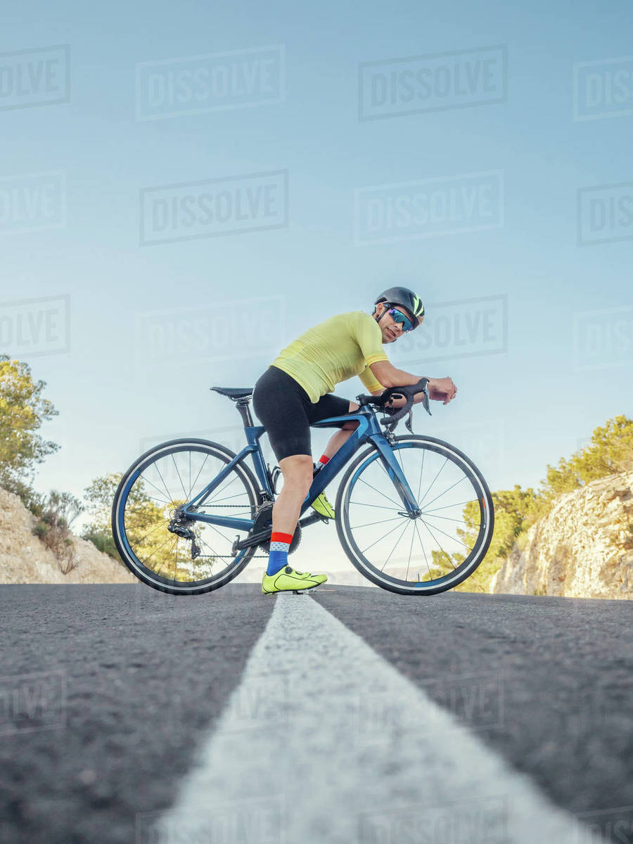 healthy man resting while riding a bicycle on a mountain road in a ...