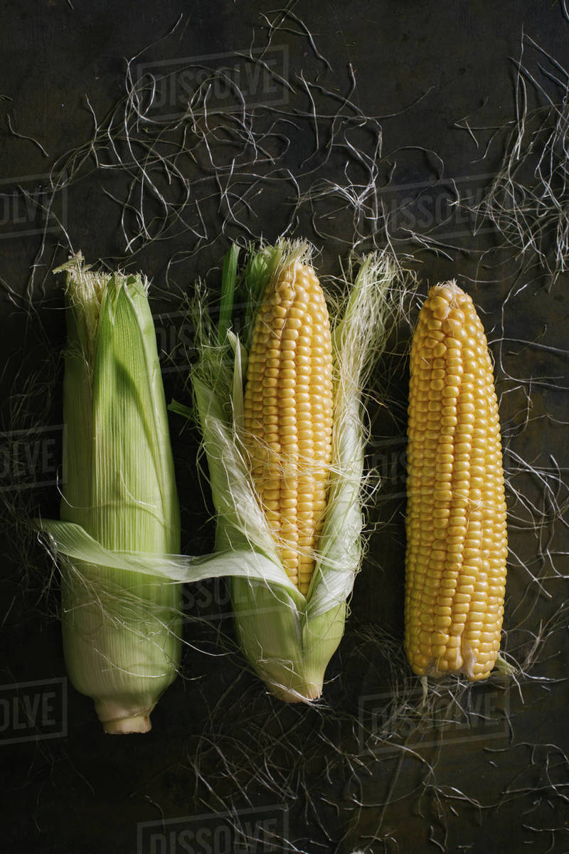 Top view of steps of fresh ripe corn peeling on black table - Royalty ...