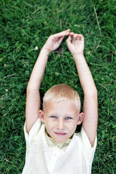 Overhead cheerful blond haired boy in white shirt looking at camera ...