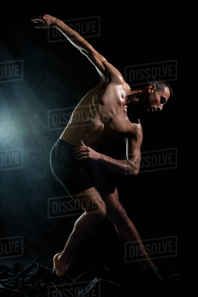 Full body of faceless tanned sporty shirtless dancer in shorts raising ...