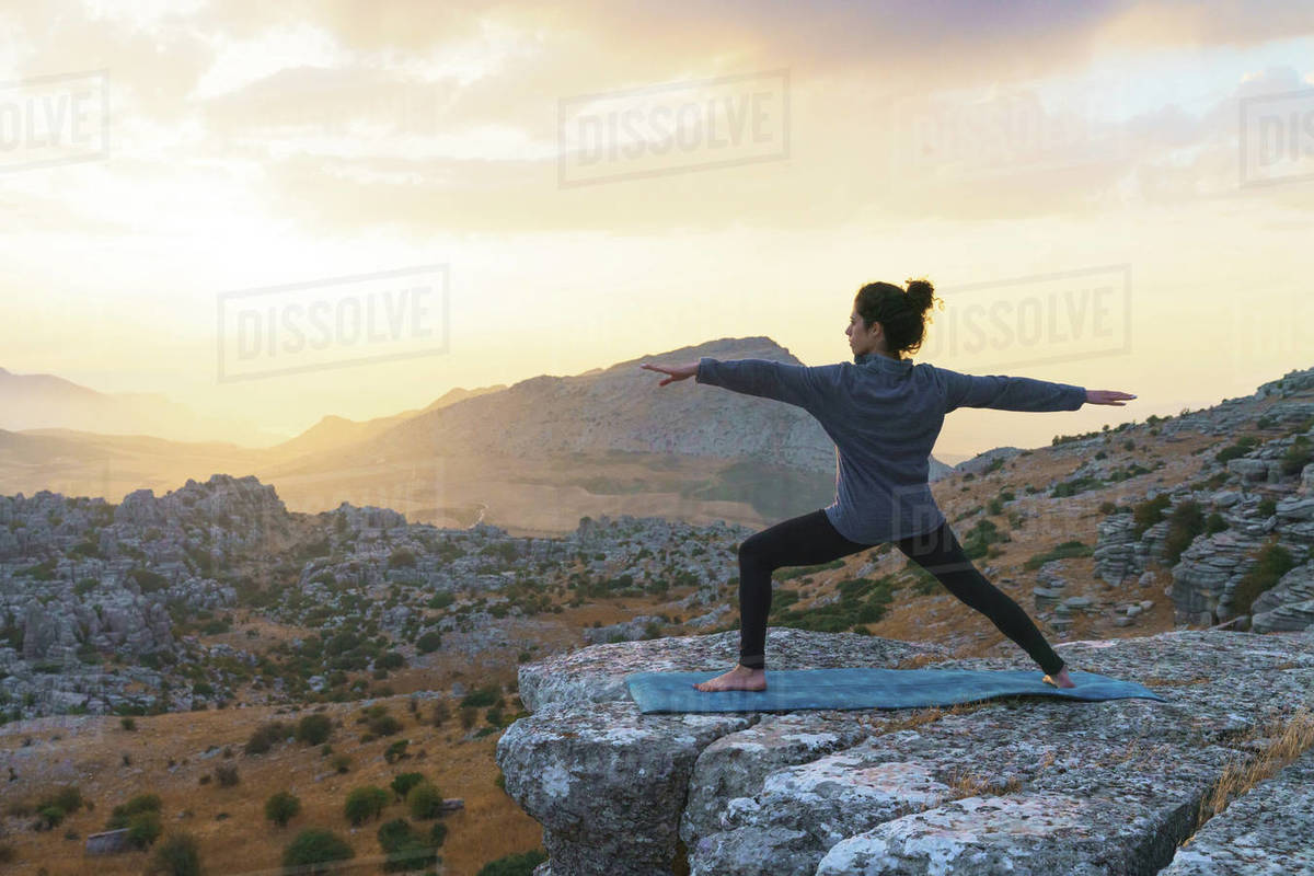 Full body of barefoot female standing in warrior pose on top of ...