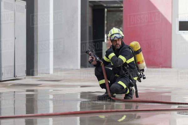 Contemplative unshaven firefighter in uniform with stripes and ...