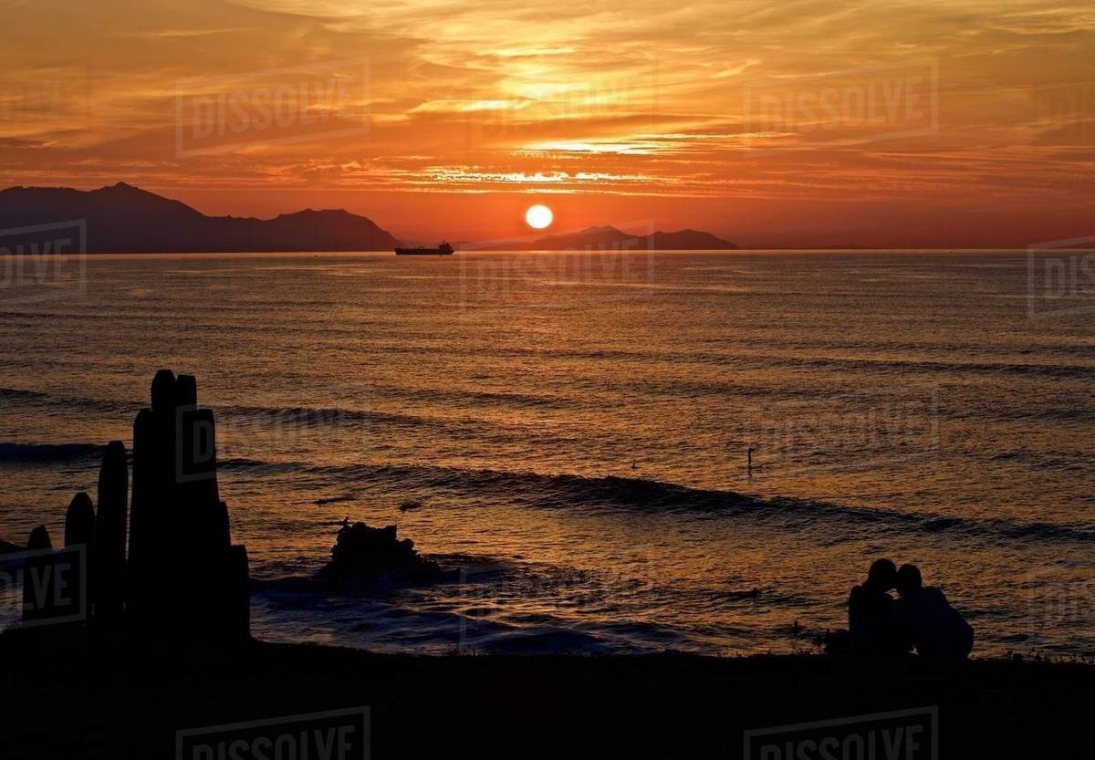 Loving couple embracing while standing against sunset sky - Stock Photo ...