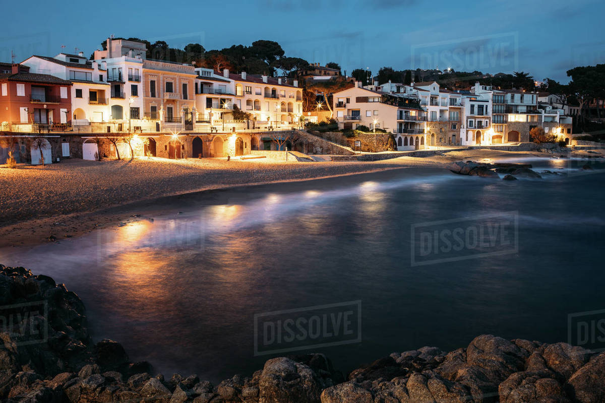 Crystal dark blue water reflecting lights on lantern on shore with ...