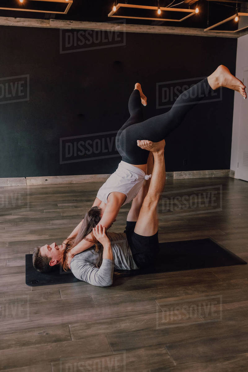 Side view of joyful athletic man with young female partner practicing ...