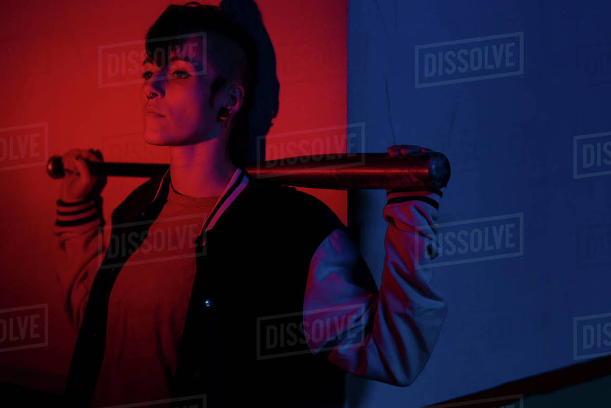 Unconventional woman with modern hairstyle standing against wall with ...