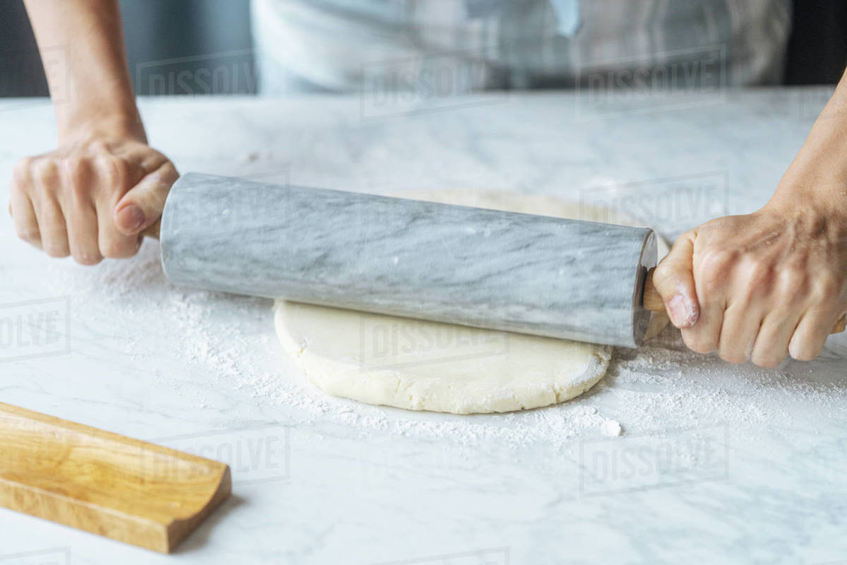 From above crop qualified cook rolling dough with marble rolling pin on ...
