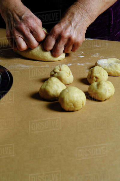 Unrecognizable lady rolling small balls from soft dough while cooking ...
